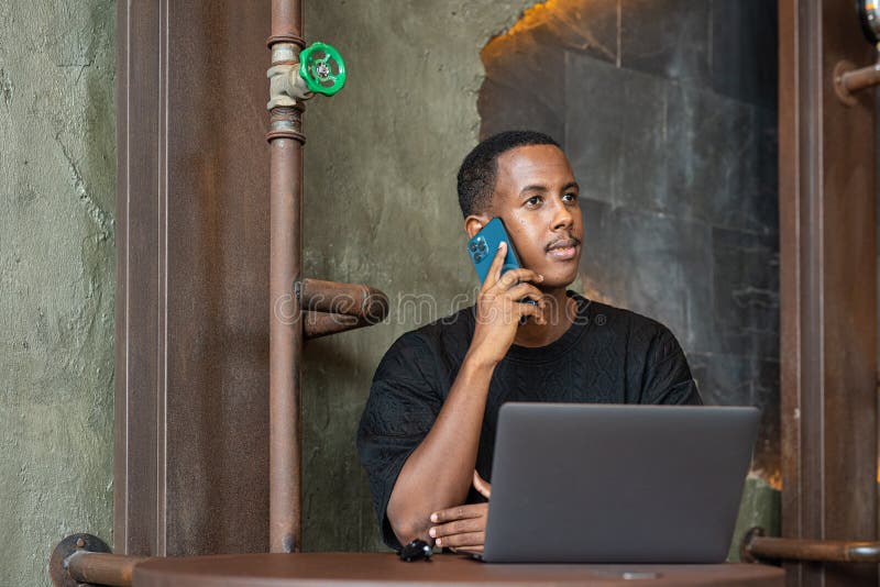 African Businessman Sitting at Coffee Shop while Using Laptop Computer ...