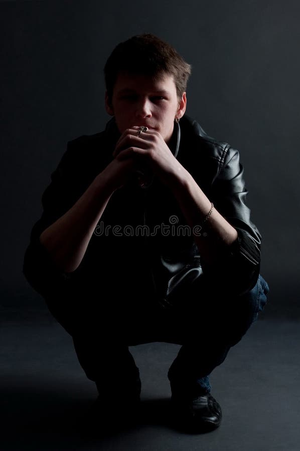 Portrait of Handsome Boy, Man Sits Squatting in Shadow in Studio Stock ...