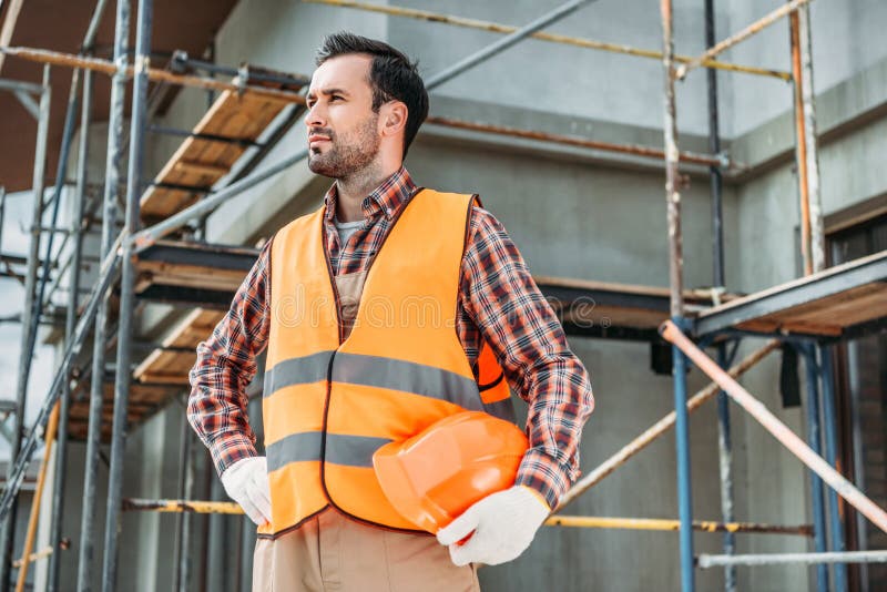 Handsome Builder in Reflective Vest Holding Helmet while Standing in ...