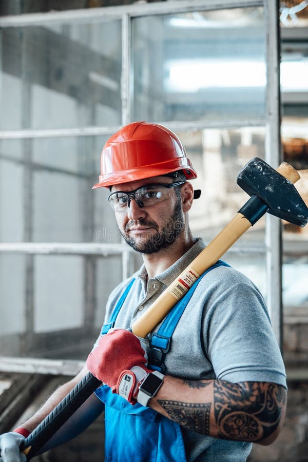 Handsome Builder Stands by the Window and Holds a Huge Hammer Stock ...