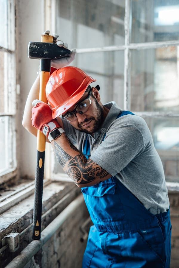 Handsome Builder Stands by the Window and Holds a Huge Hammer Stock ...