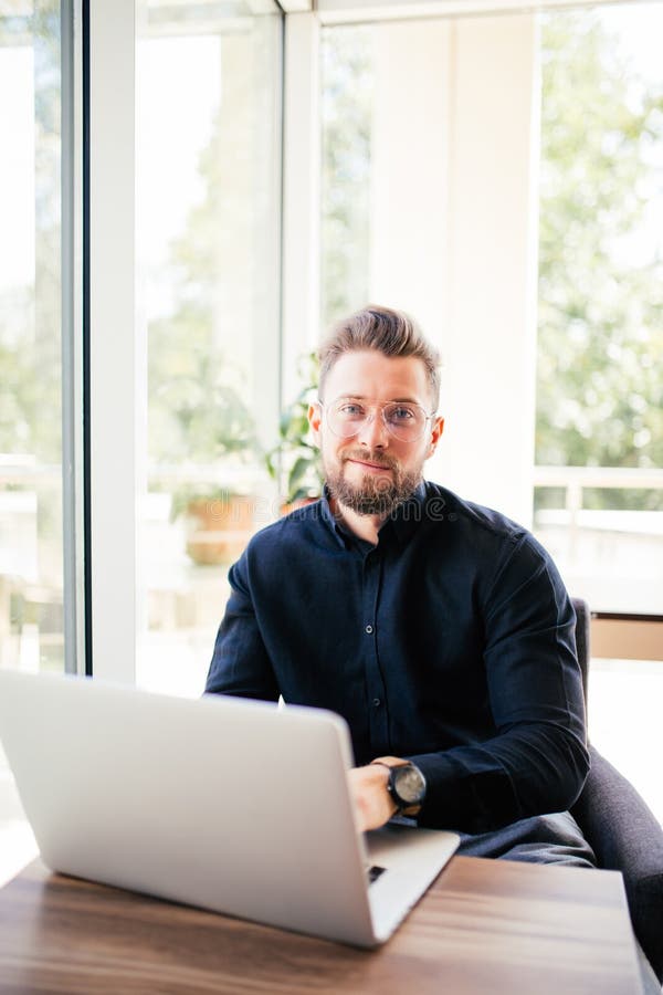 Handsome Businessman In Casual Wear And Eyeglasses Is Using A Laptop In