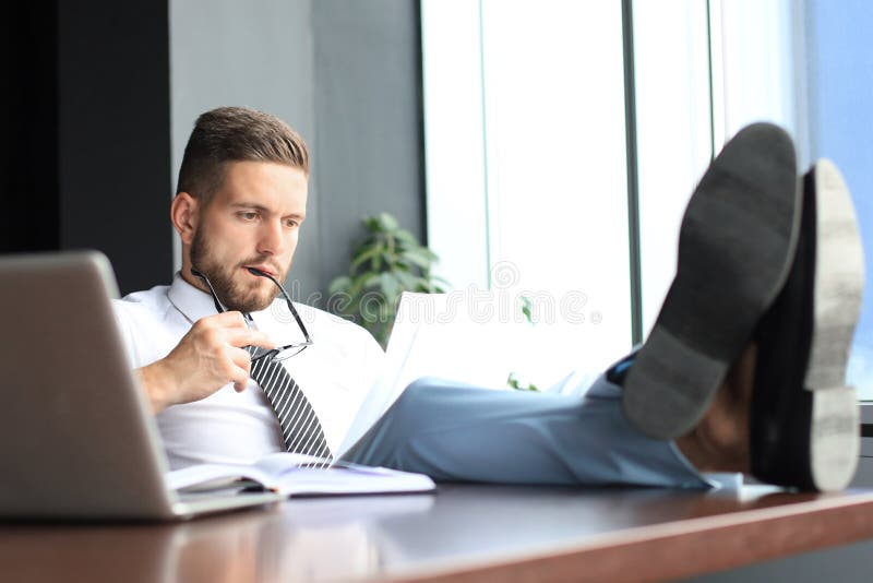 Handsome Businessman Sitting with Legs on Table and Examing Documents ...