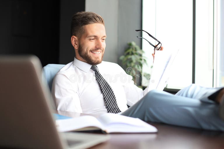 Handsome Businessman Sitting with Legs on Table and Examing Documents ...