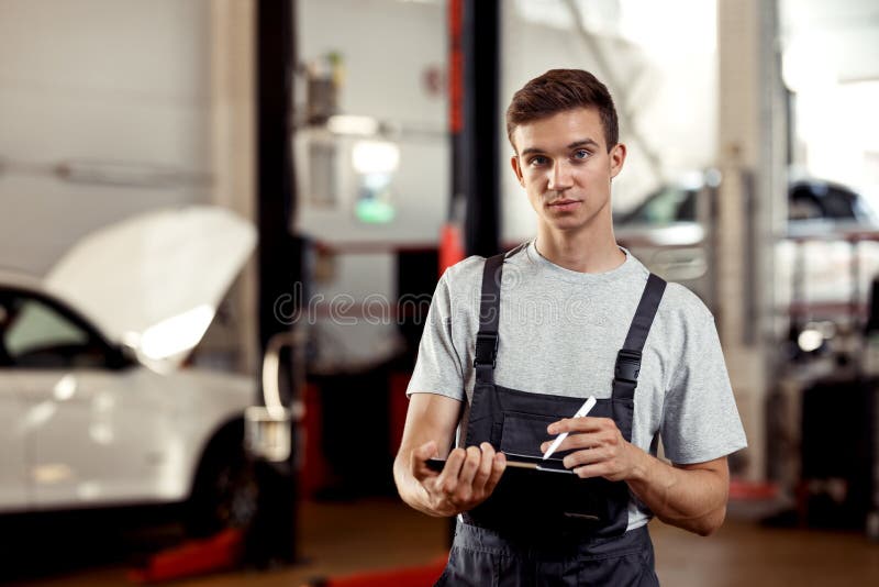 A Handsome Car Mechanic is Filling in a Form while at Work Stock Image ...