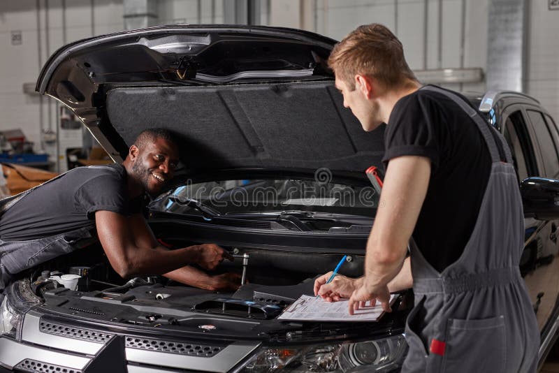 Handsome Caucasian Guy is Making Notes while Repairing Hood of Car ...