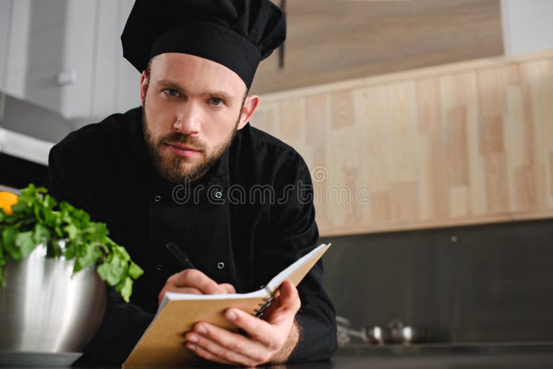 Handsome Chef Writing Down New Recipe To Notebook at Restaurant Kitchen ...