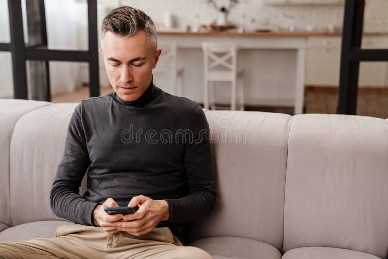 Handsome Concentrated Man Using Mobile Phone while Sitting on Couch ...