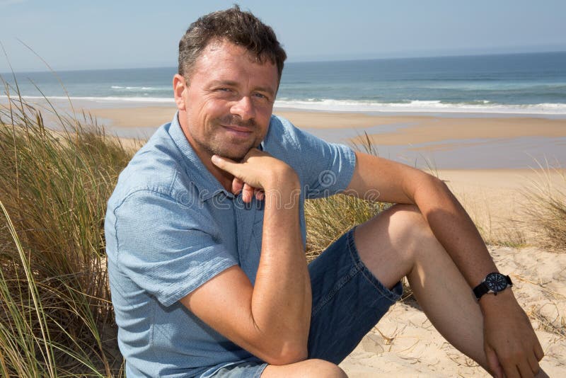 Handsome and Confident Man Smiling and Sitting at the Beach Stock Photo ...