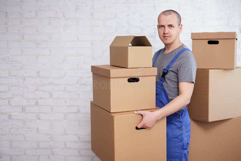 Handsome Man Loader Holding Many Boxes â€“ Copy Space Over White Brick ...