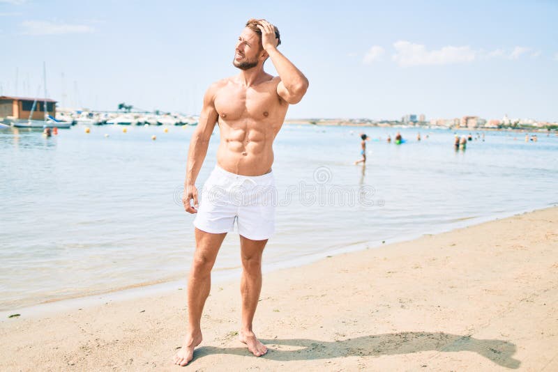 Handsome Fitness Caucasian Man At The Beach On A Sunny Day Showing