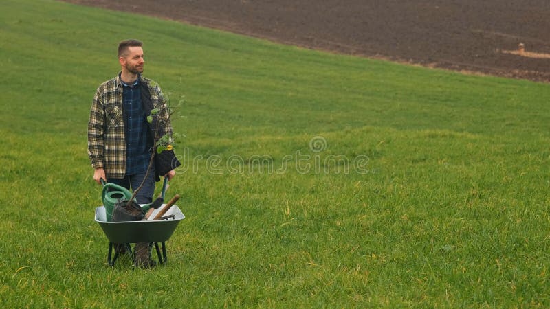 The Handsome Gardener Walking with a Wheelbarrow through the Field ...