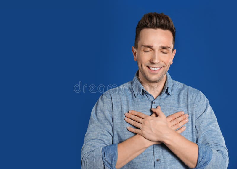 Handsome Grateful Man with Hands on Chest Against Light Grey Background ...