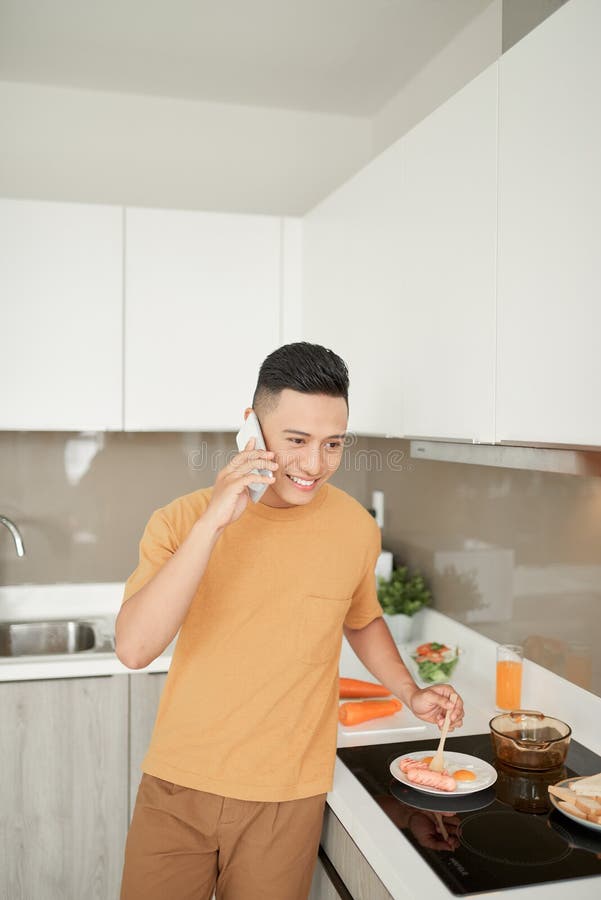 Handsome Guy is Talking on the Mobile Phone and Smiling while Cooking ...