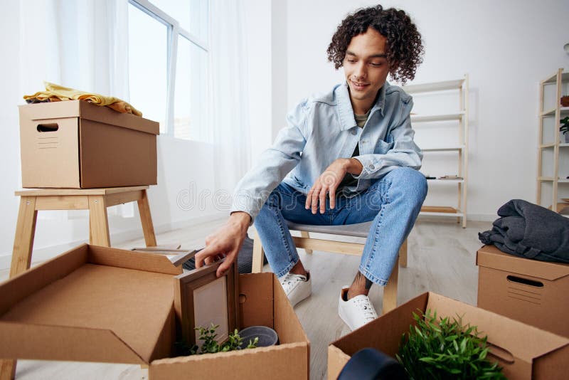 Handsome Guy Unpacking Things from Boxes in the Room Sorting Things Out ...