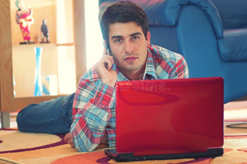 Handsome Guy Using Laptop and Phone Lying on Floor Stock Photo - Image ...