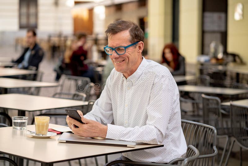Smiling Old Man Checking Smart Phone while Working on Computer in ...