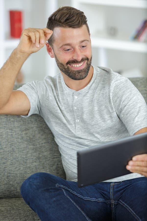 Handsome Happy Man Looking at Tablet on Sofa Stock Image - Image of ...