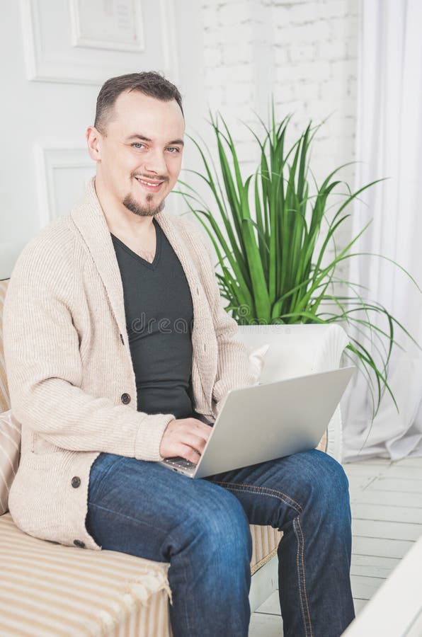 Handsome Happy Man Working Using Laptop on the Couch at Home Stock ...
