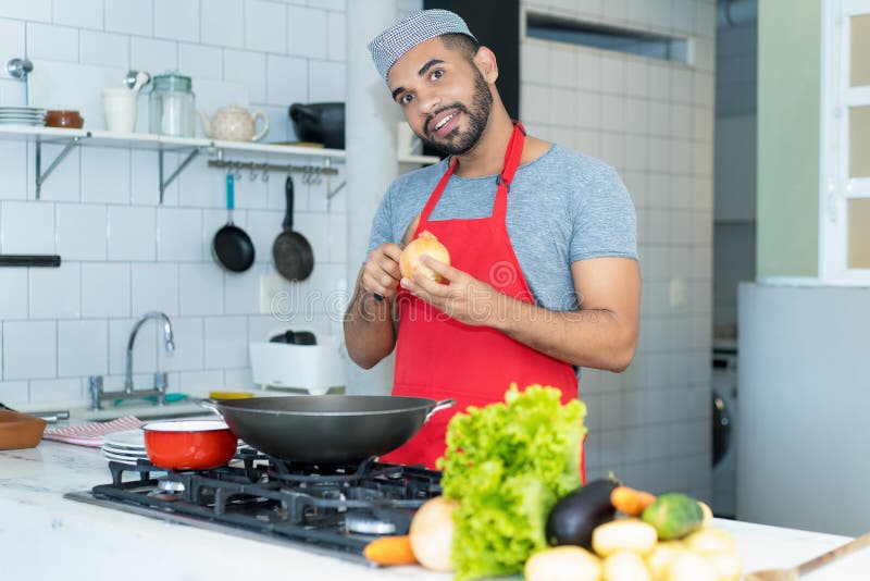 Handsome Hispanic Cook with Red Apron Preparing Food at Kitchen Stock ...