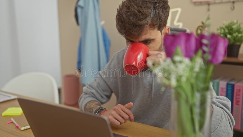 Handsome Hispanic Man Drinking Coffee at Home while Working on Laptop ...