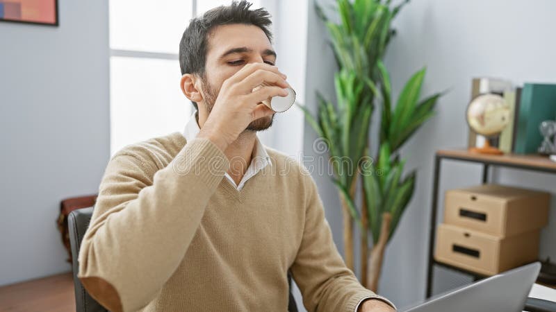 Handsome Hispanic Man Drinking Coffee in a Modern Office, Representing ...