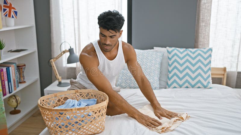 Handsome Hispanic Man Folding Laundry in a Modern Bedroom Stock Image - Image of neat, cleaning ...