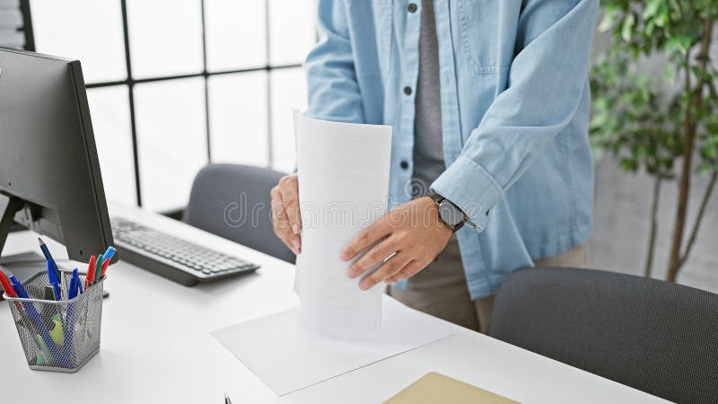 Handsome Hispanic Man Reviewing Documents in a Modern Office Setting ...