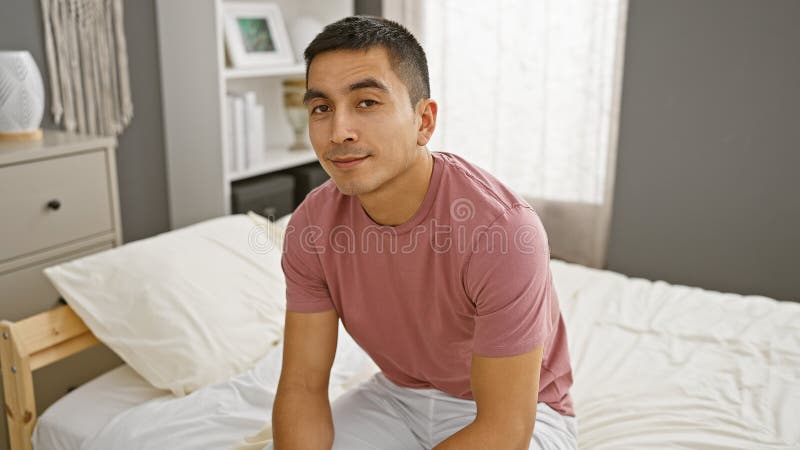 Handsome Hispanic Man Sitting on Bed in a Well-lit Modern Bedroom Stock ...