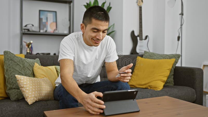 Handsome Hispanic Man Smiling Using Tablet in Modern Living Room Stock ...