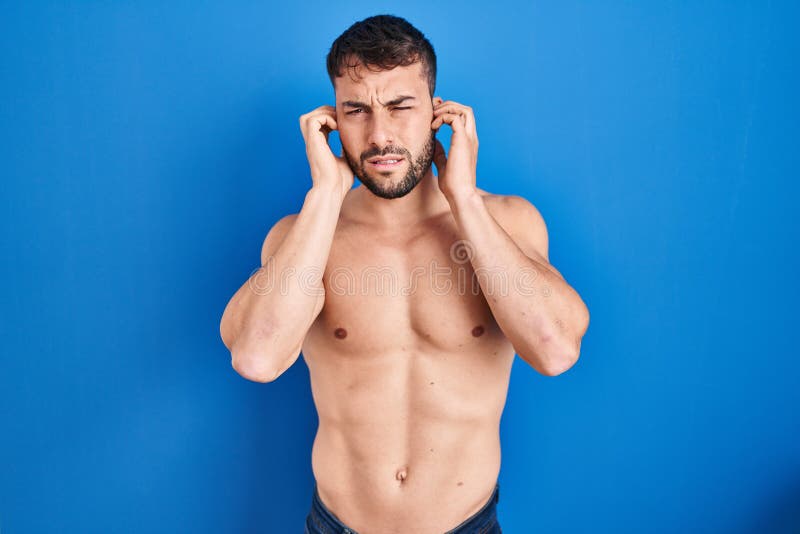 Handsome Hispanic Man Standing Shirtless Covering Ears With Fingers