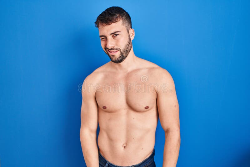 Handsome Hispanic Man Standing Shirtless Winking Looking At The Camera