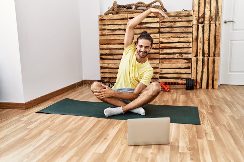 Handsome Hispanic Man Stretching Looking at Tutorial on Laptop at the ...