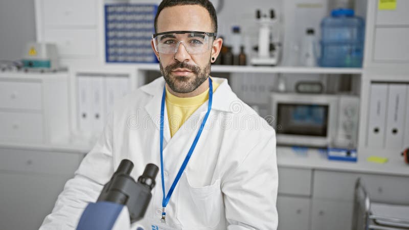 Handsome Hispanic Scientist with a Beard Engages with a Microscope in a ...