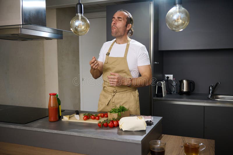 Handsome Hispanic Young Man Tasting Ingredients while Cooking Dinner at ...