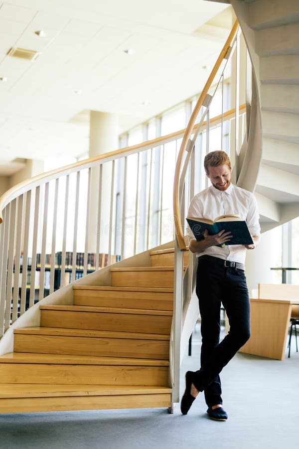 Handsome Intelligent Guy Reading a Book in a Library Stock Image ...