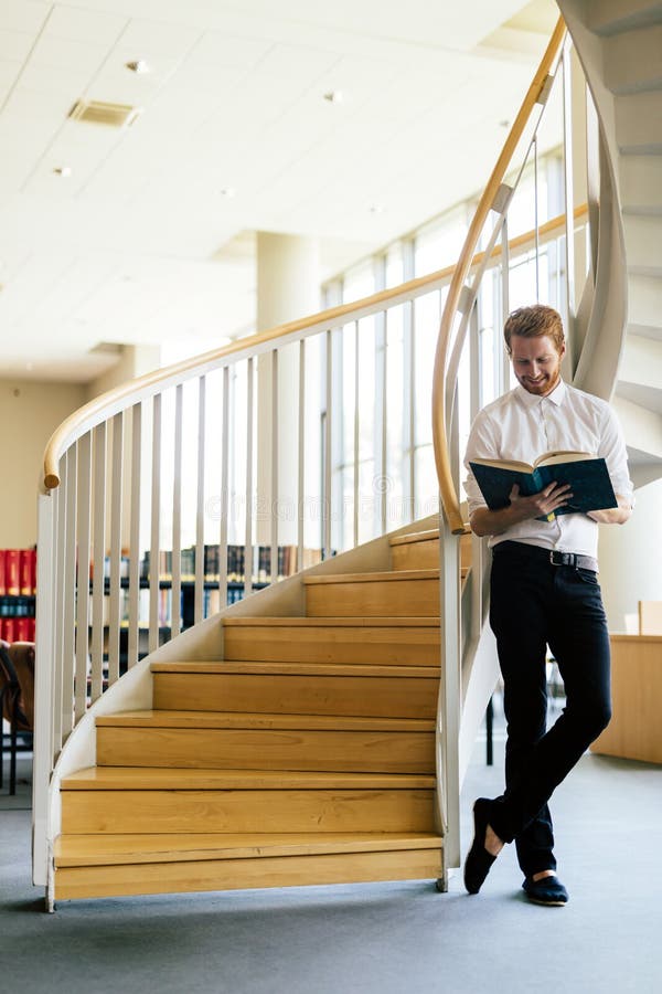 Handsome Intelligent Guy Reading a Book in a Library Stock Image ...