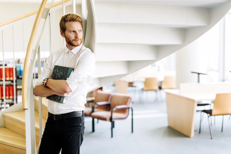 Handsome Intelligent Guy Reading a Book in a Library Stock Photo ...