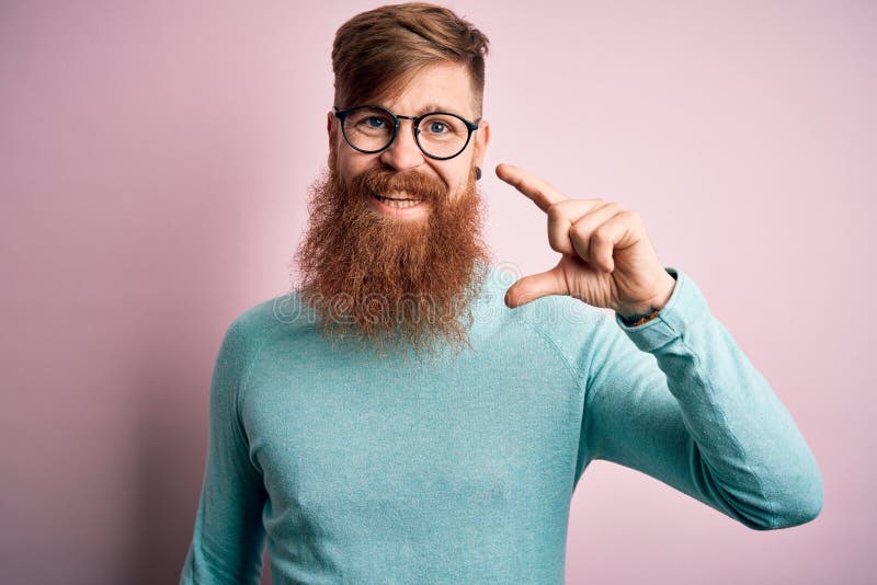 Handsome Irish Redhead Man With Beard Wearing Glasses Over Pink