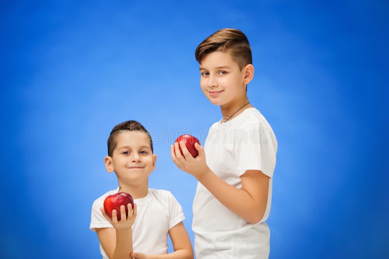 Handsome Little Boys with Two Red Apples. Studio Portrait Over Blue ...