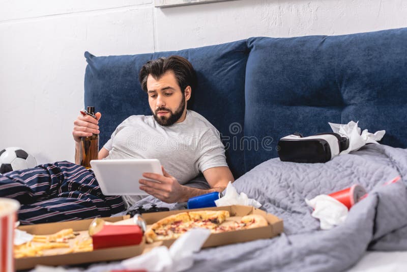 Handsome Loner Using Tablet on Bed in Bedroom and Holding Bottle Stock ...