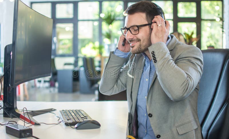Handsome Male Call Center Operator in Headset Working with Computer in ...