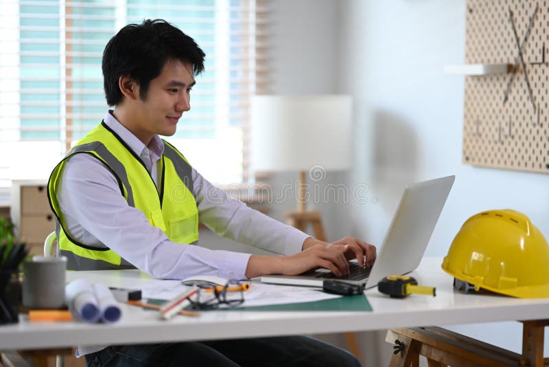 Male Construction Engineer in White Shirt and Yellow Vest Using Laptop ...