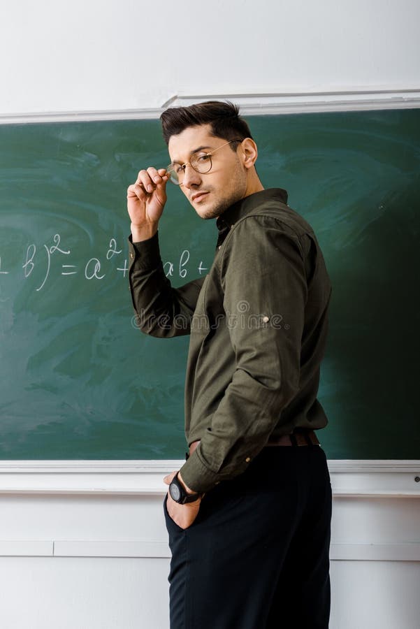 Smiling Male Teacher Looking at Camera and Writing on Chalkboard Stock ... Smiling Male Teacher Looking at Camera and Writing on Chalkboard Stock ...