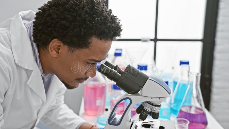 Handsome Man Analyzing Samples Under Microscope in a Modern Laboratory ...
