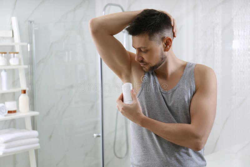 Man Applying Deodorant To Armpit in Bathroom, Closeup. Space for Text ...