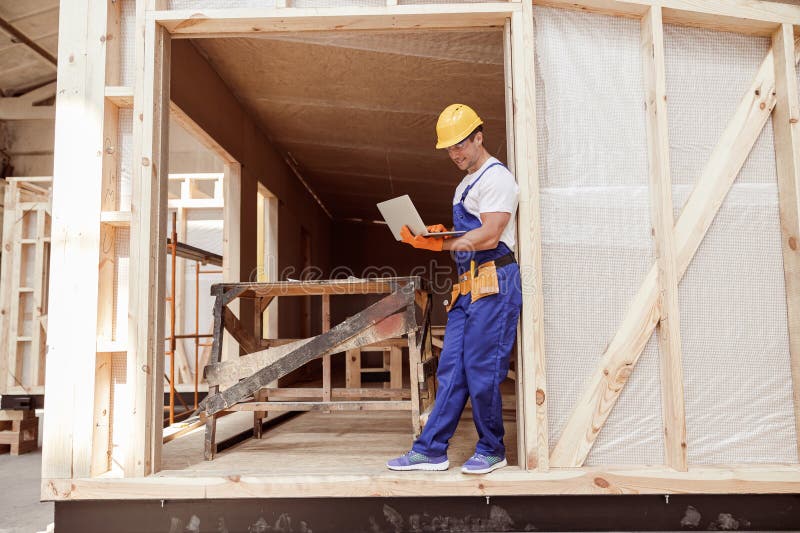 Cheerful Male Builder Using Laptop at Construction Site Stock Photo ... Cheerful Male Builder Using Laptop at Construction Site Stock Photo ...