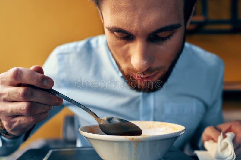 A Handsome Man with a Beard Eats Borscht in a Plate at a Table in a ...