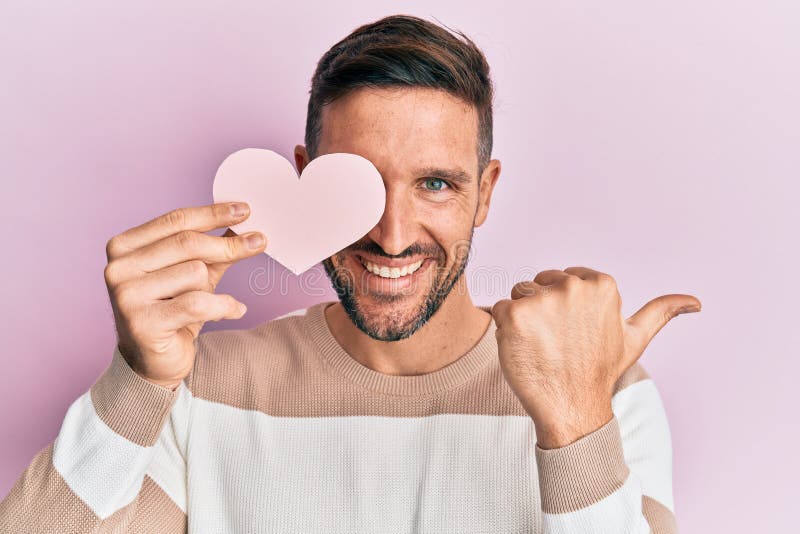 Handsome Man With Beard Holding Heart Shape Paper Pointing Thumb Up To
