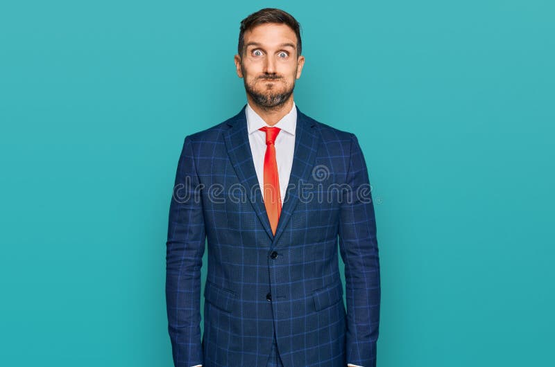 Handsome Man With Beard Wearing Business Suit And Tie Puffing Cheeks